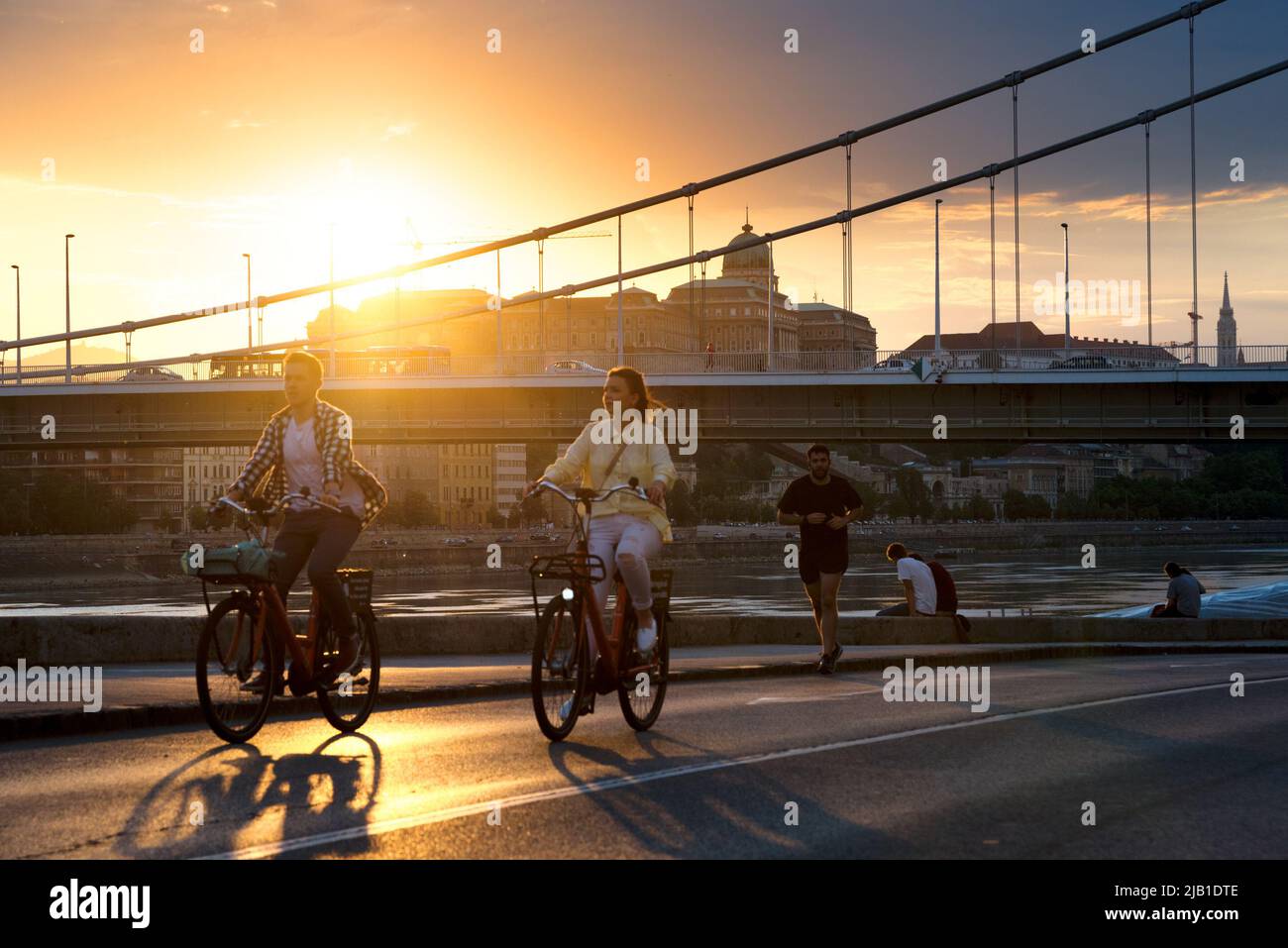 People cycling and jogging by the river in a city, sunset tine Stock ...