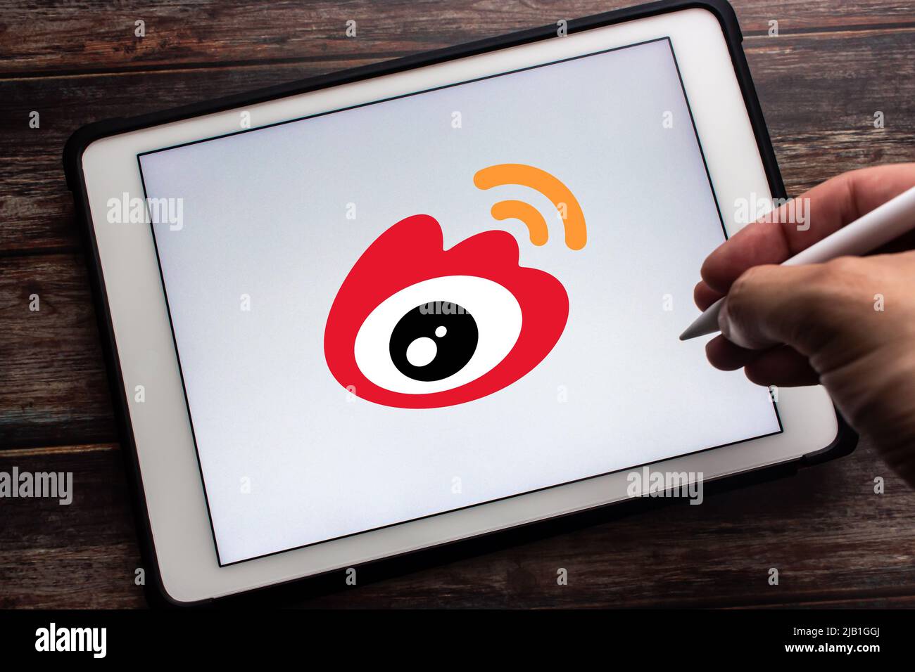 Kumamoto, JAPAN - May 27 2021 : Logo of Sina Weibo on tablet. Man holding pen. Weibo is a ...