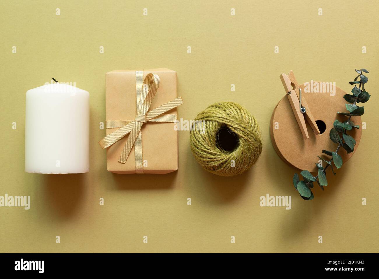 Brown gift box, string reel, candle on khaki green background. flat lay ...