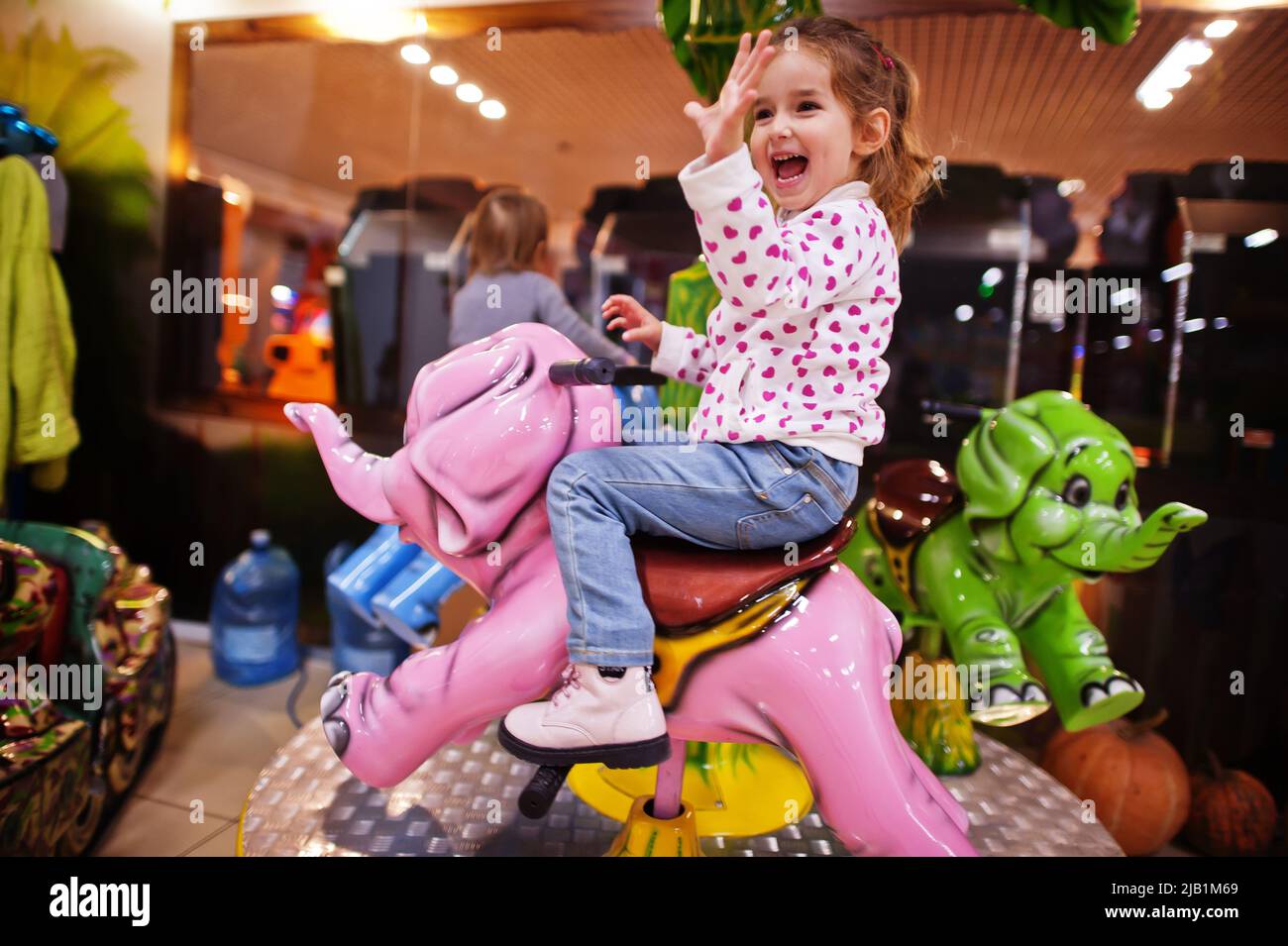 Two sisters rides an elephant carousel in fun children center Stock ...