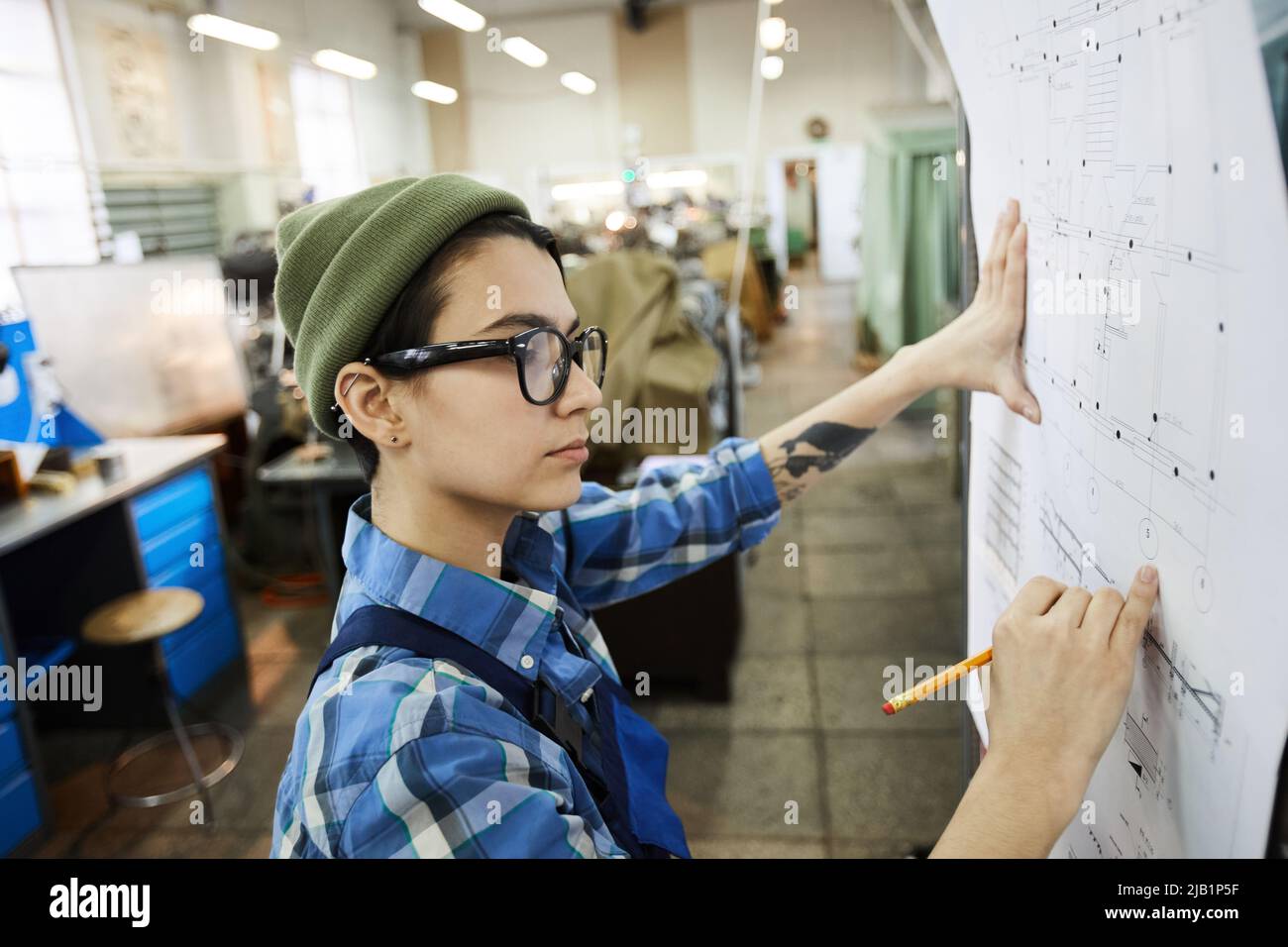 Serious busy tenacious lady in glasses standing at wall and drawing on ...
