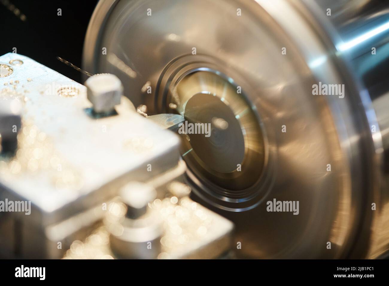 Close-up of rotating metal workpiece with cutting tool at production ...