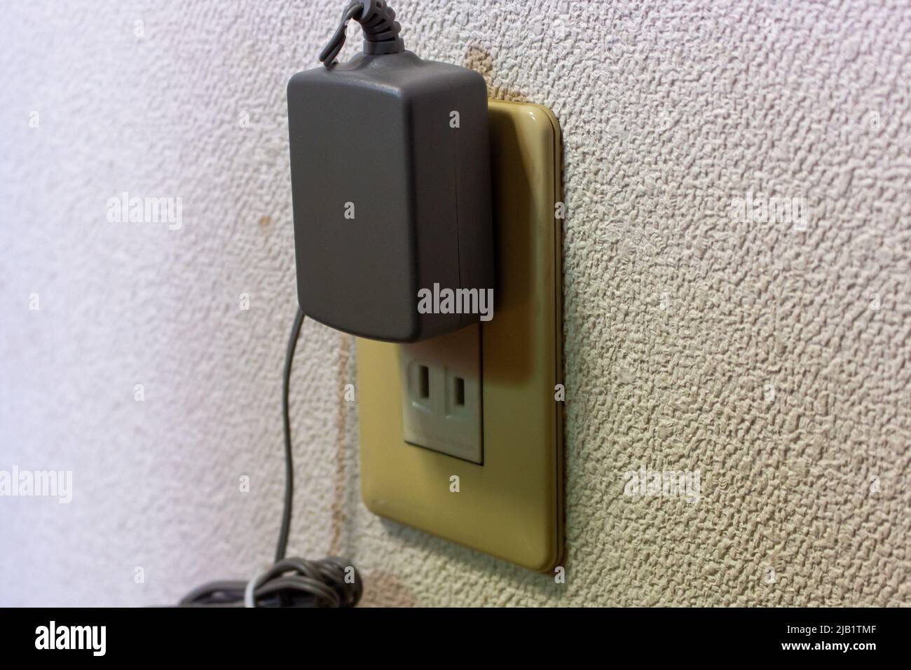 Closeup an old A-type AC adapter which plugged into the outlet at home ...