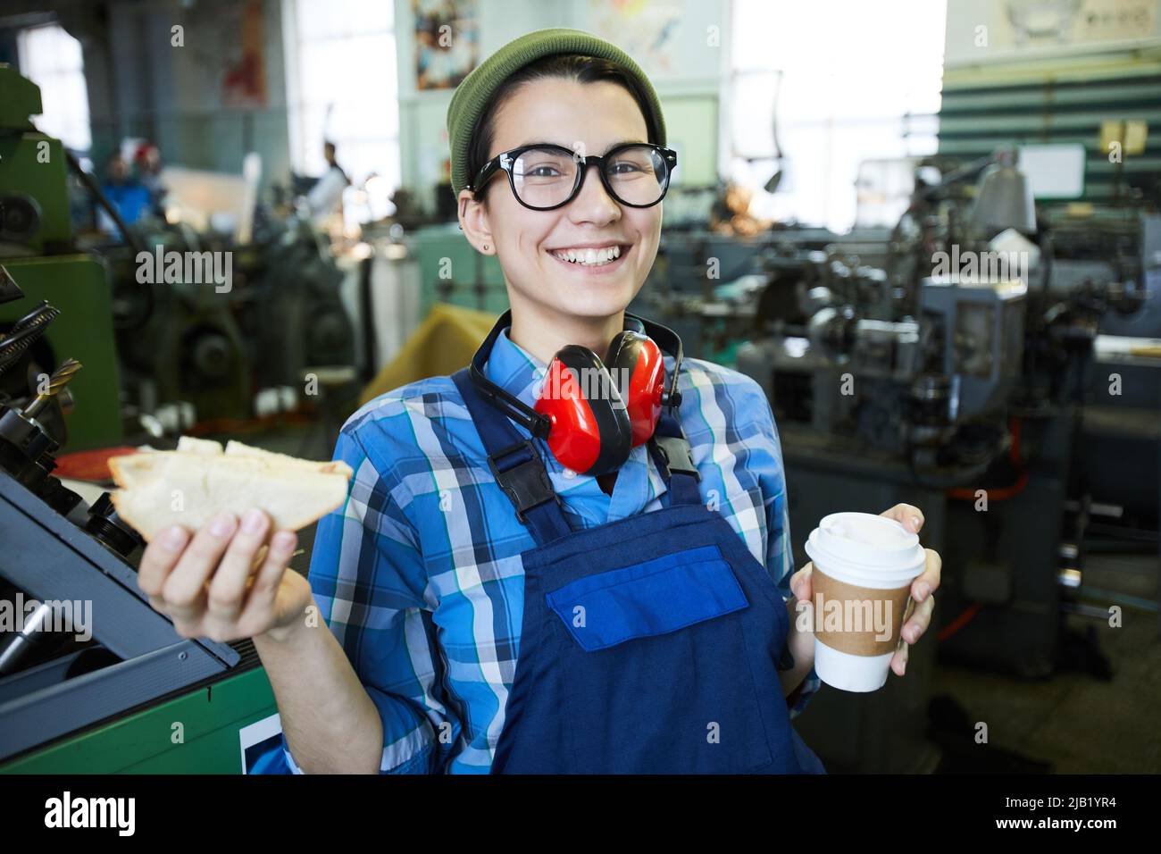 Happy excited lady worker in glasses eating sandwich and drinking ...