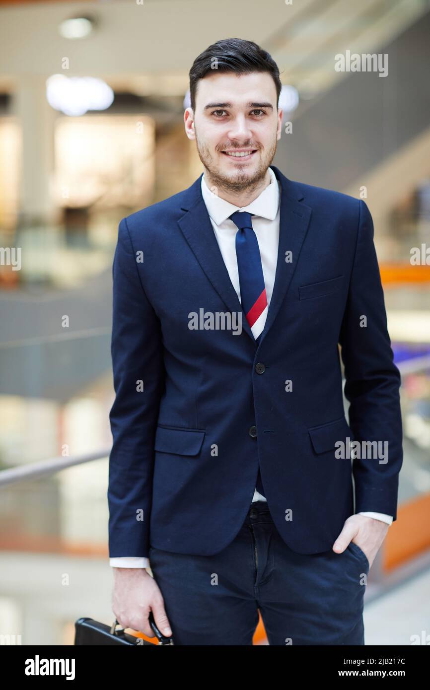 Smiling handsome young male bank manager in suit standing in business ...
