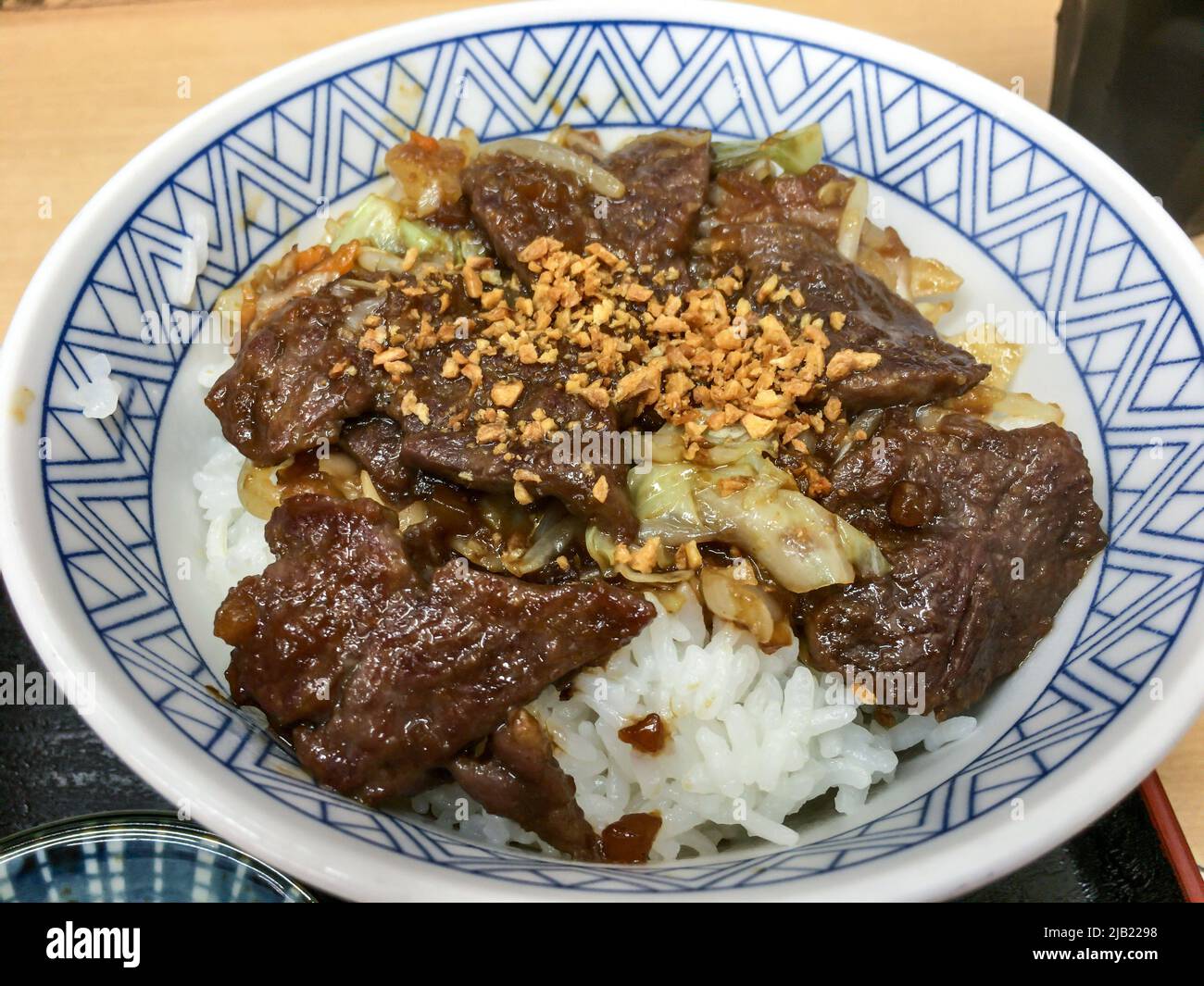 The closeup Yakiniku Don, grilled beef meats (yakiniku) topped on a bowl of rice (donburi) with ...