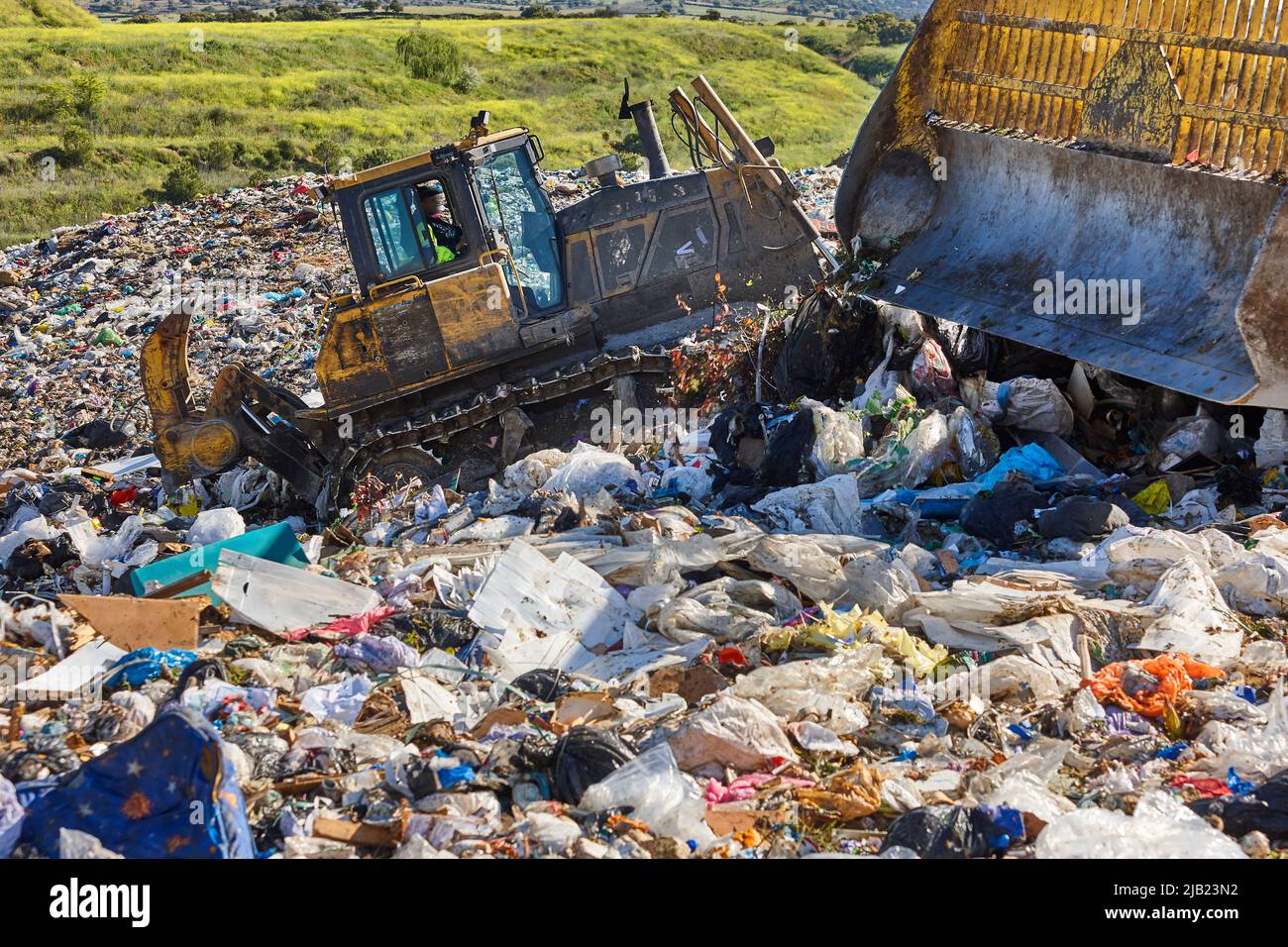 Heavy machinery shredding garbage in an open air landfill. Waste Stock ...