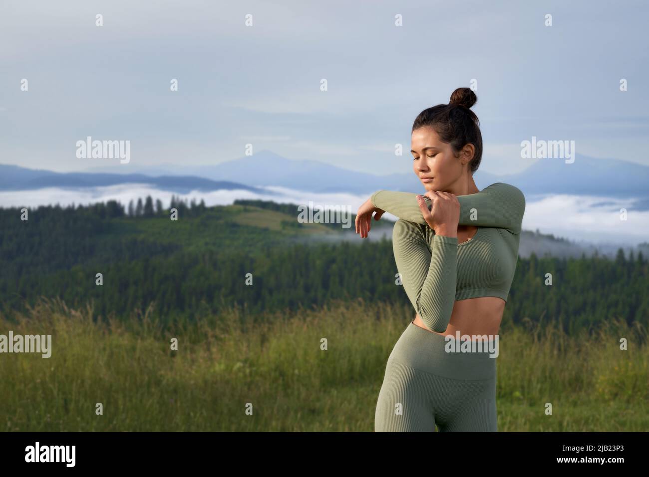 Active young woman in sport clothes stretching body during outdoors ...