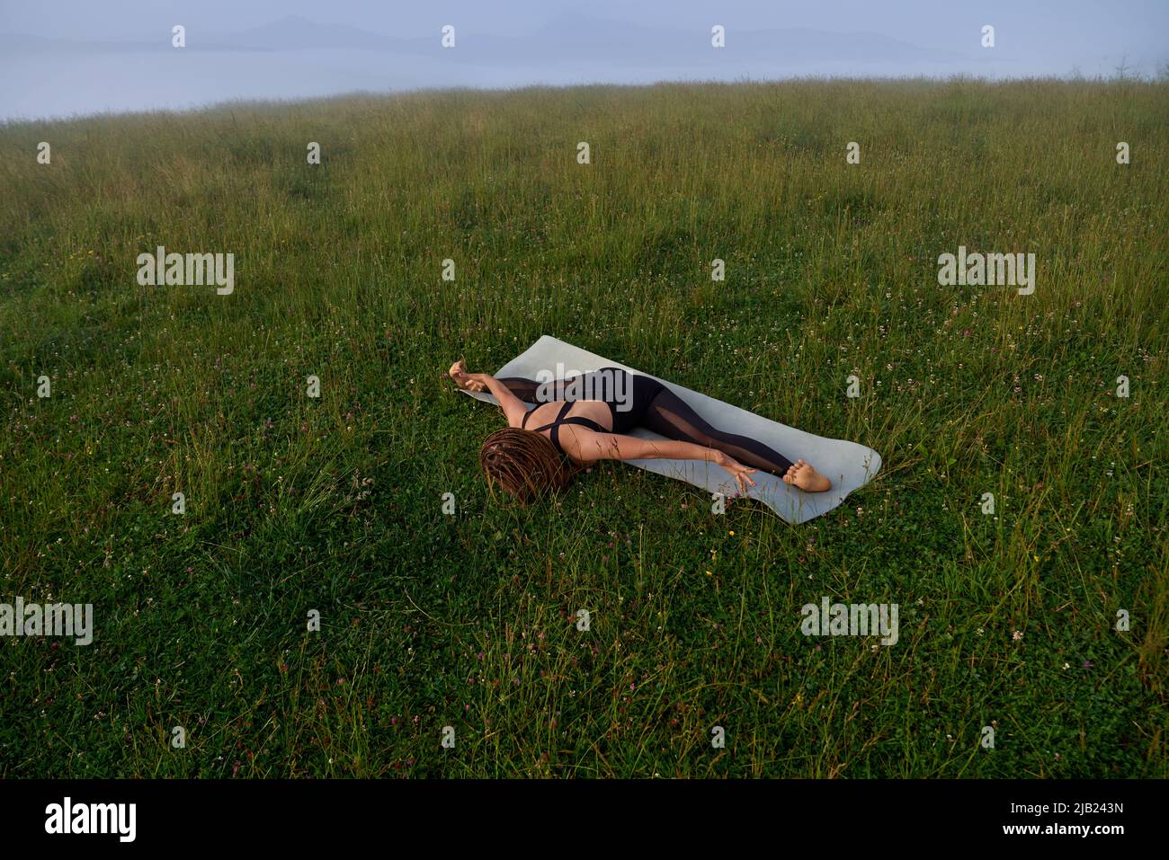 Flexible young woman in sport clothes doing splits on yoga mat among ...