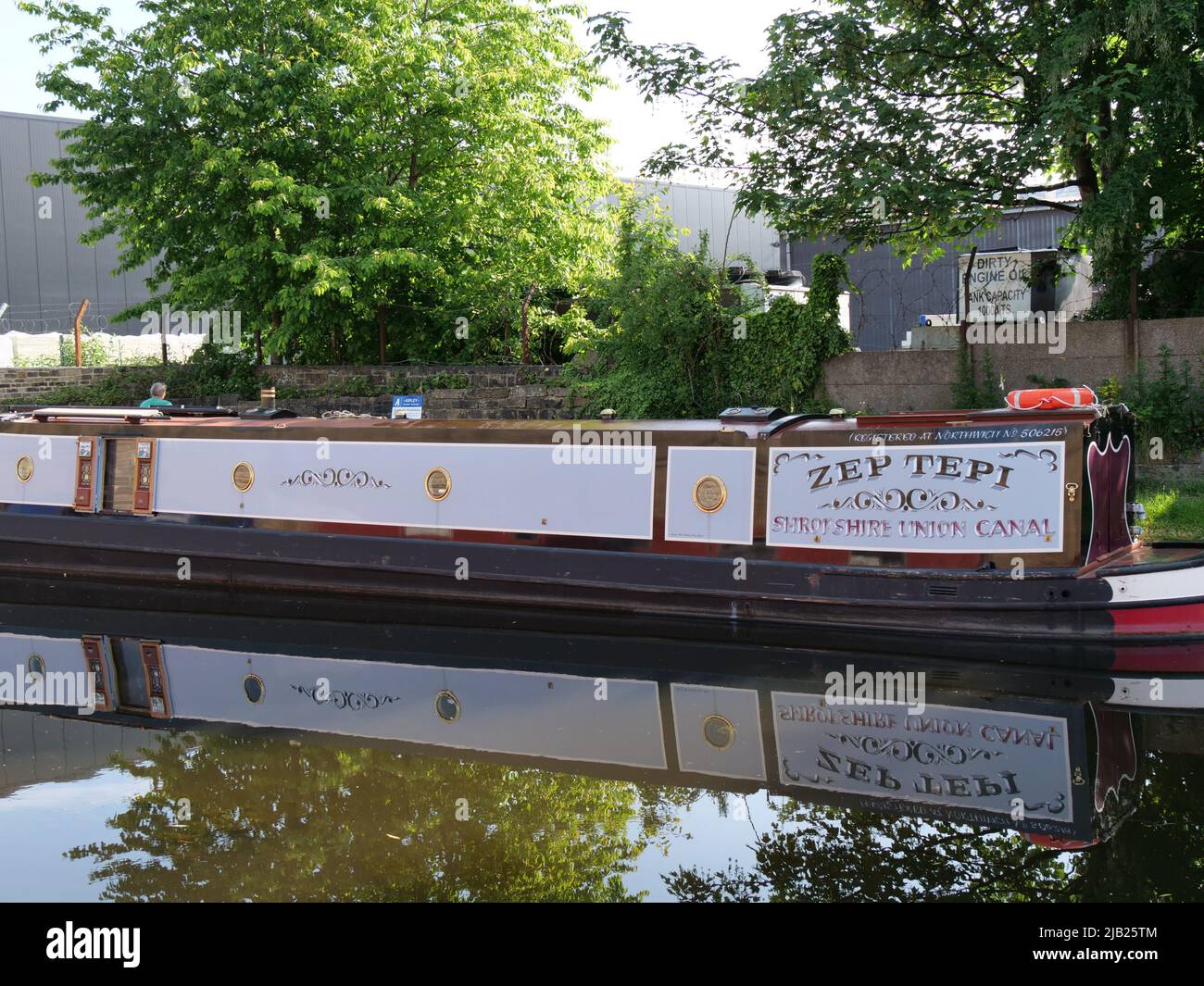 White canal barge narrow boat moored by towpath with reflections in ...