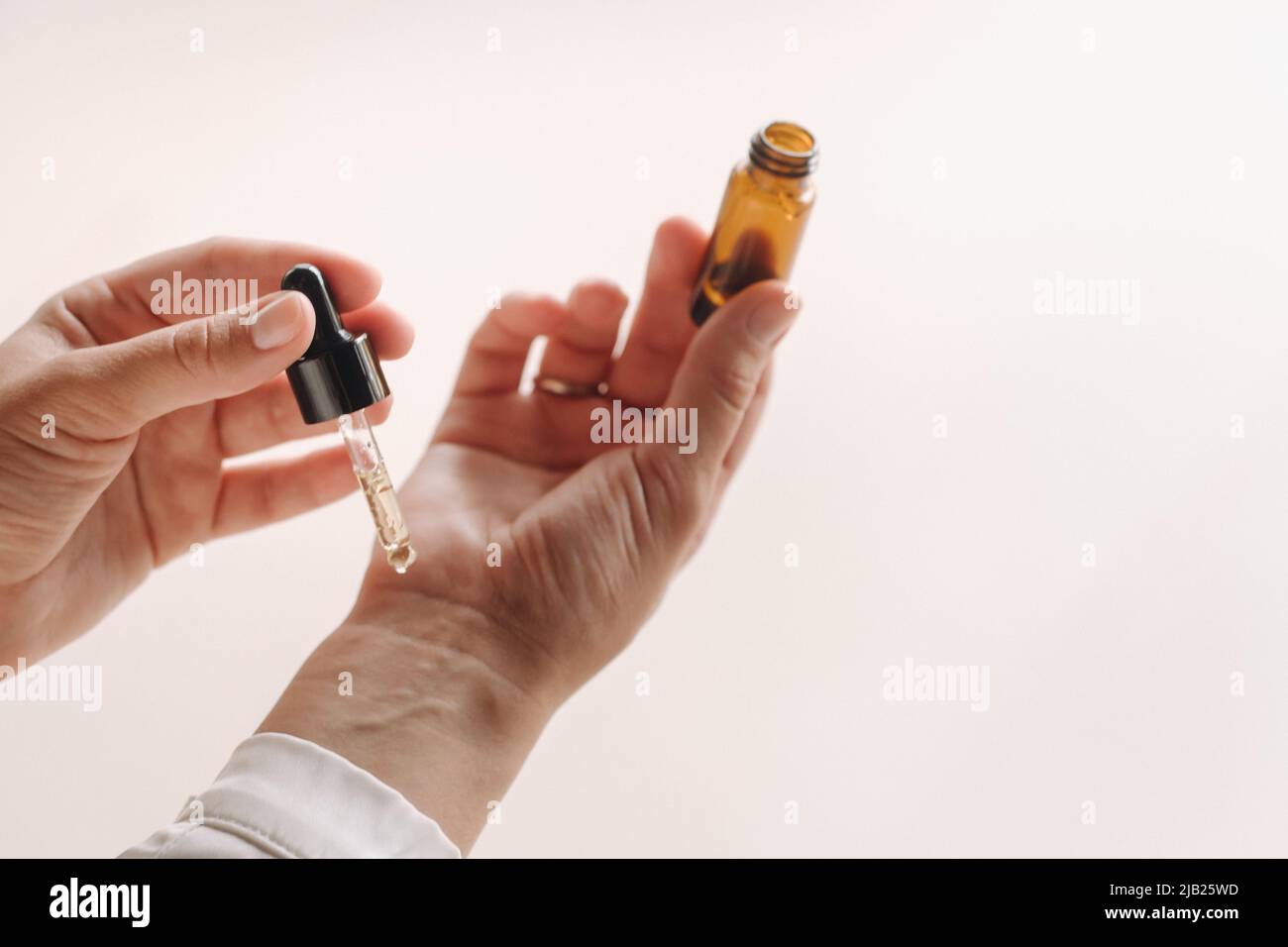 Close-up of a Woman's hands applying essential oil on her wrist indoors ...
