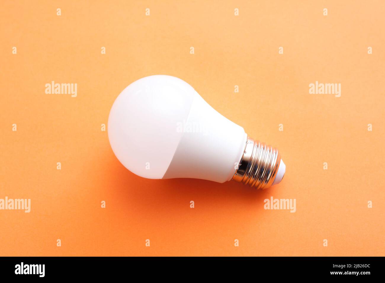 White economy light bulb on orange background Stock Photo - Alamy