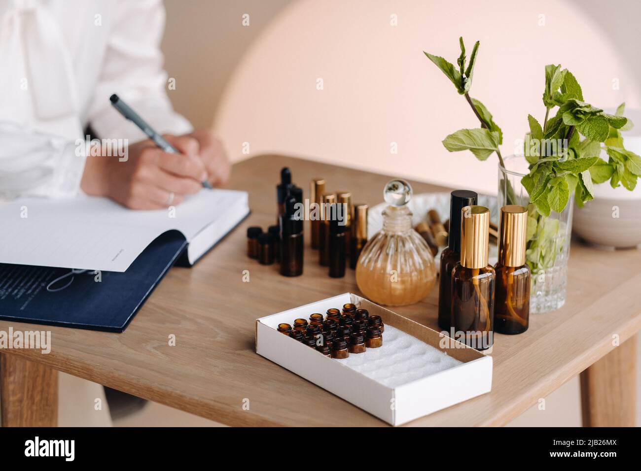 Close-up of female hands holding a bottle of essential oil and writing ...