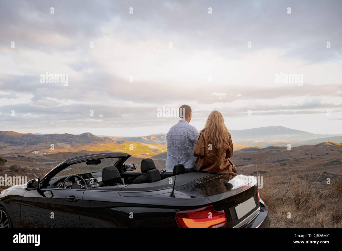 Back view of young couple in love man and woman looking at mountains ...