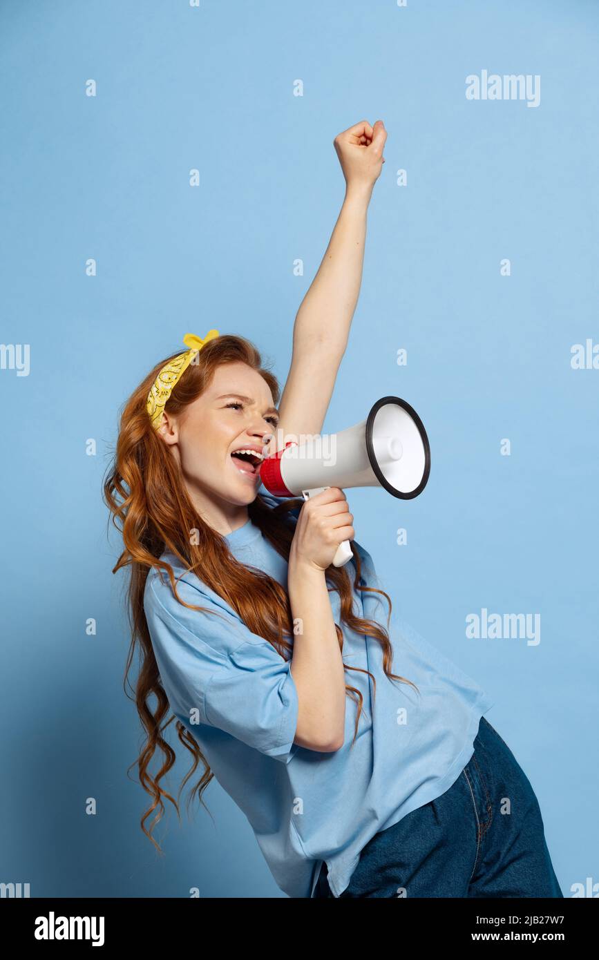 Excited young redhead girl, student shouting at megaphone isolated on ...