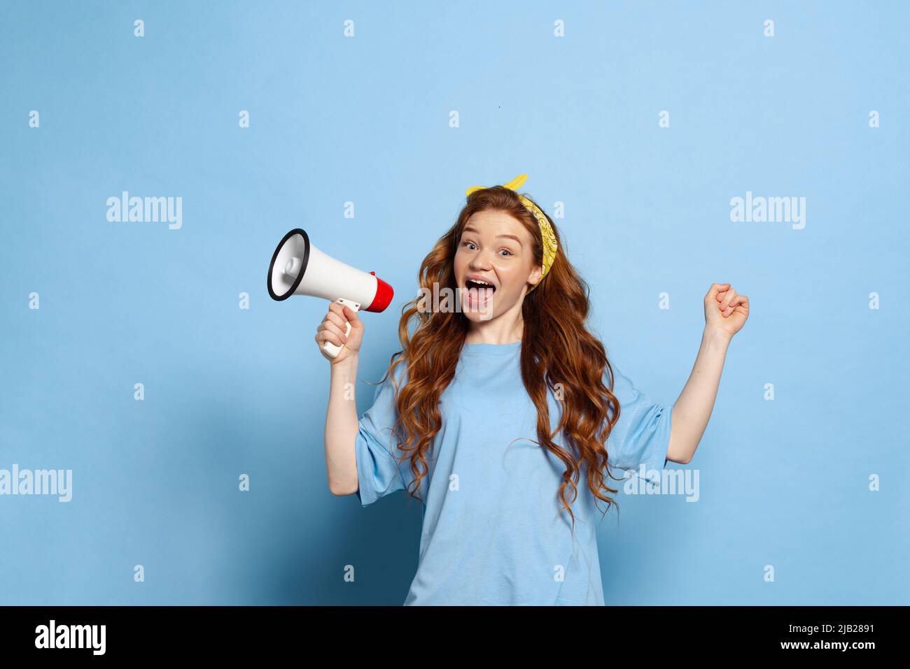 Excited young redhead girl, student shouting at megaphone isolated on ...