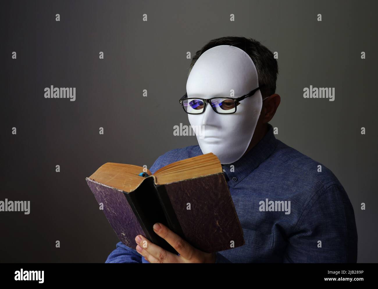a masked man reading a book Stock Photo - Alamy