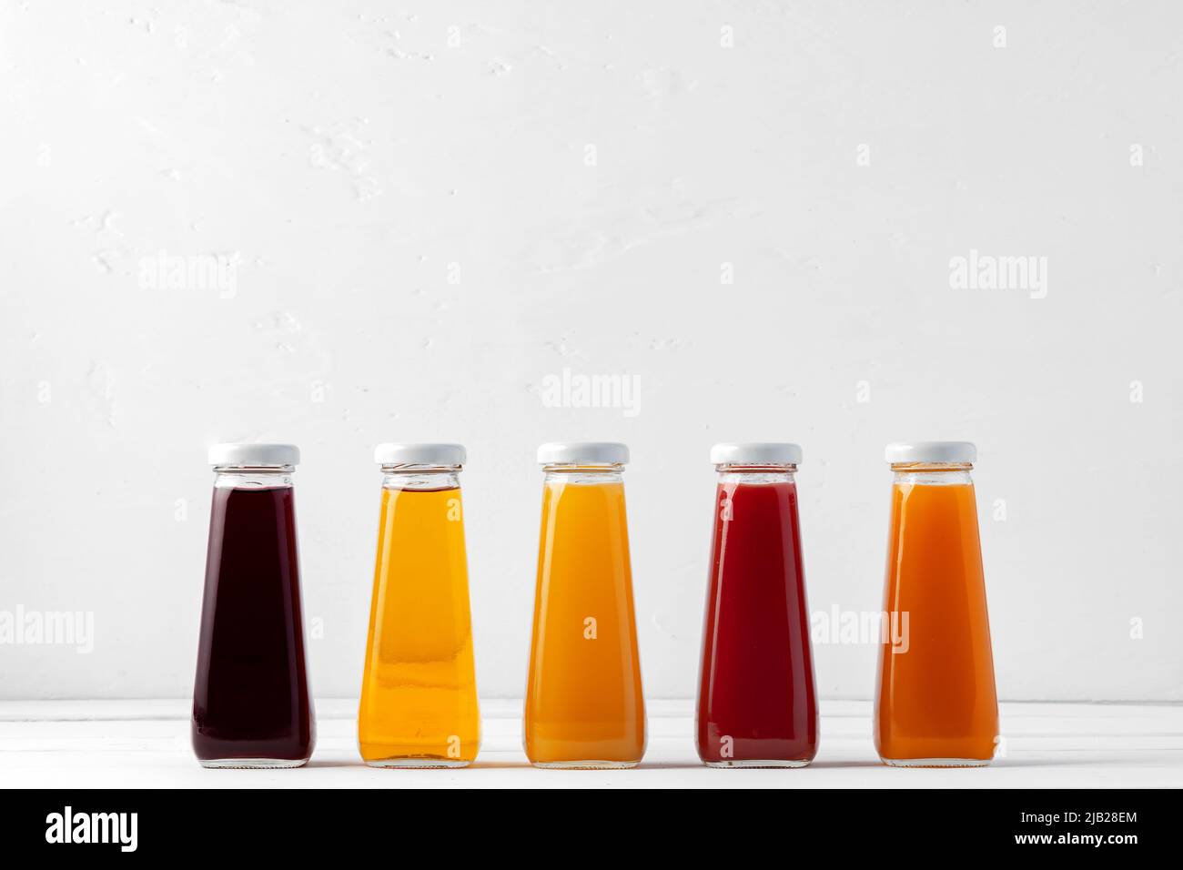 Glass bottles of different juices on white background Stock Photo - Alamy