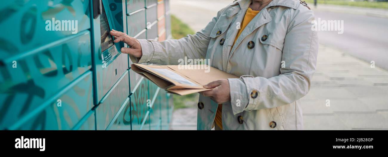 Caucasian woman send or receive parcel with yellow self service post ...