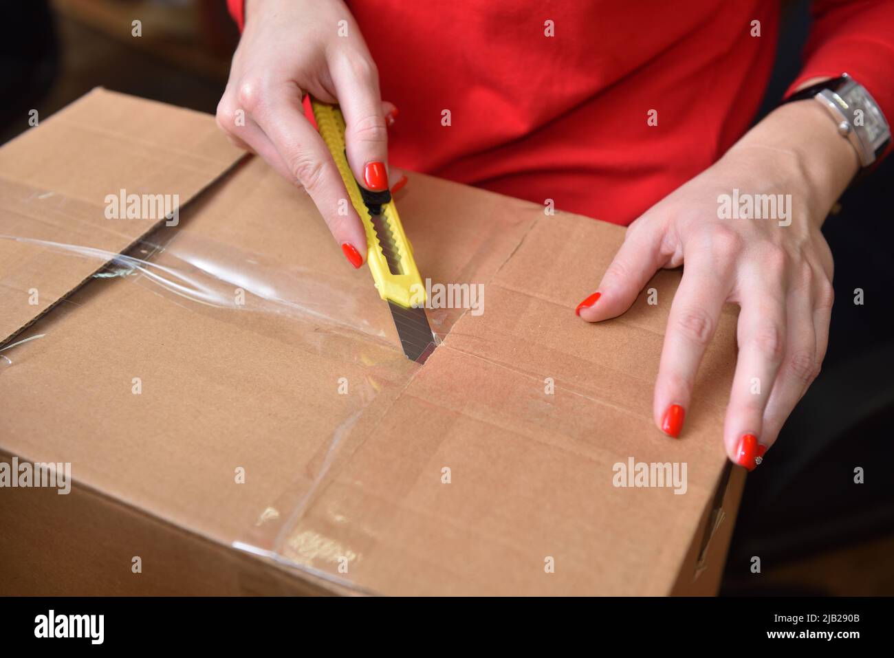 Hands opens the parcel with a clerical knife Stock Photo - Alamy