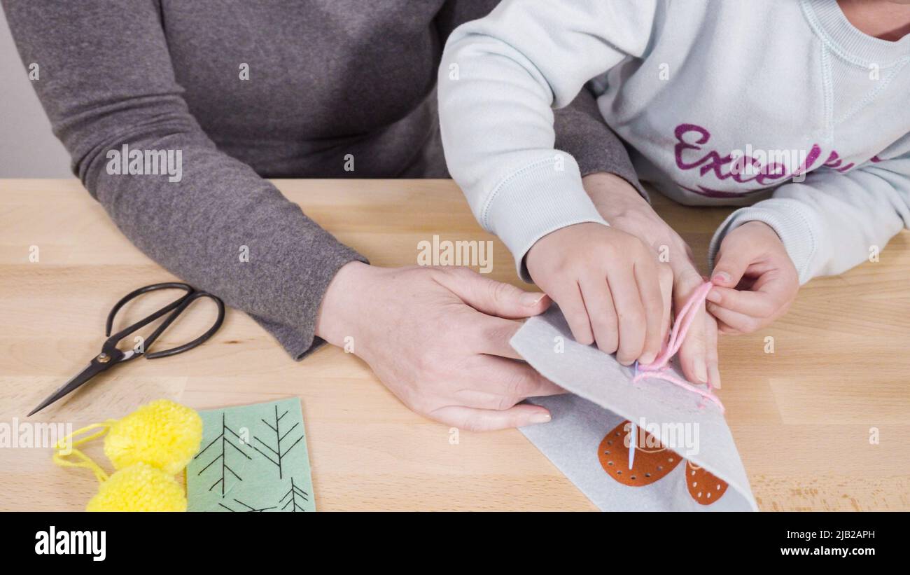Little girl learning how to sew with her mother at the craft table ...