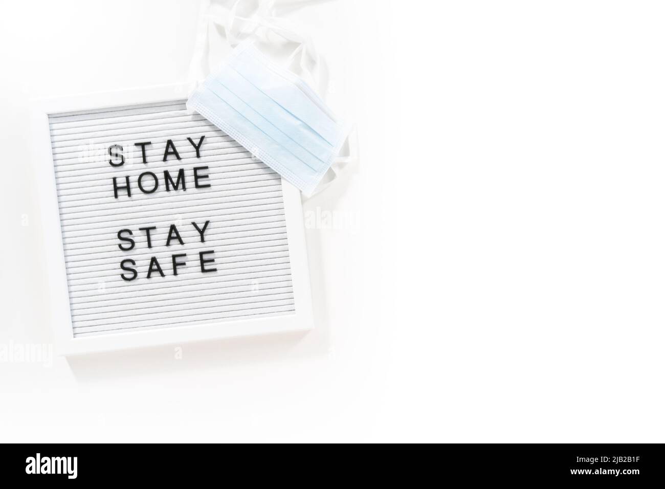 STAY HOME and STAY SAFE sign on message board with a blue medical mask ...