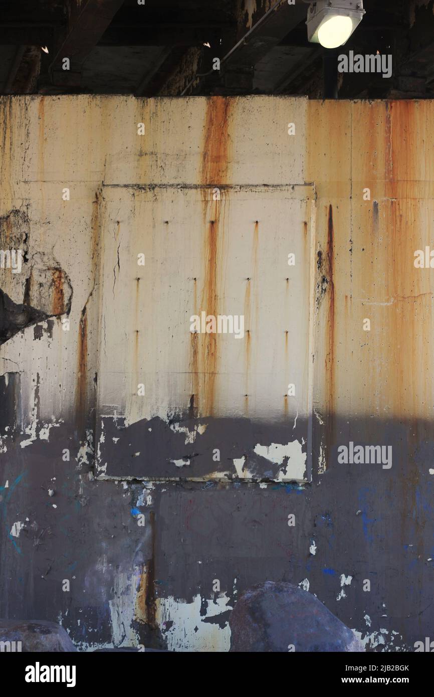 Inner city neglect of a rusted old door and entrance under the bridge ...