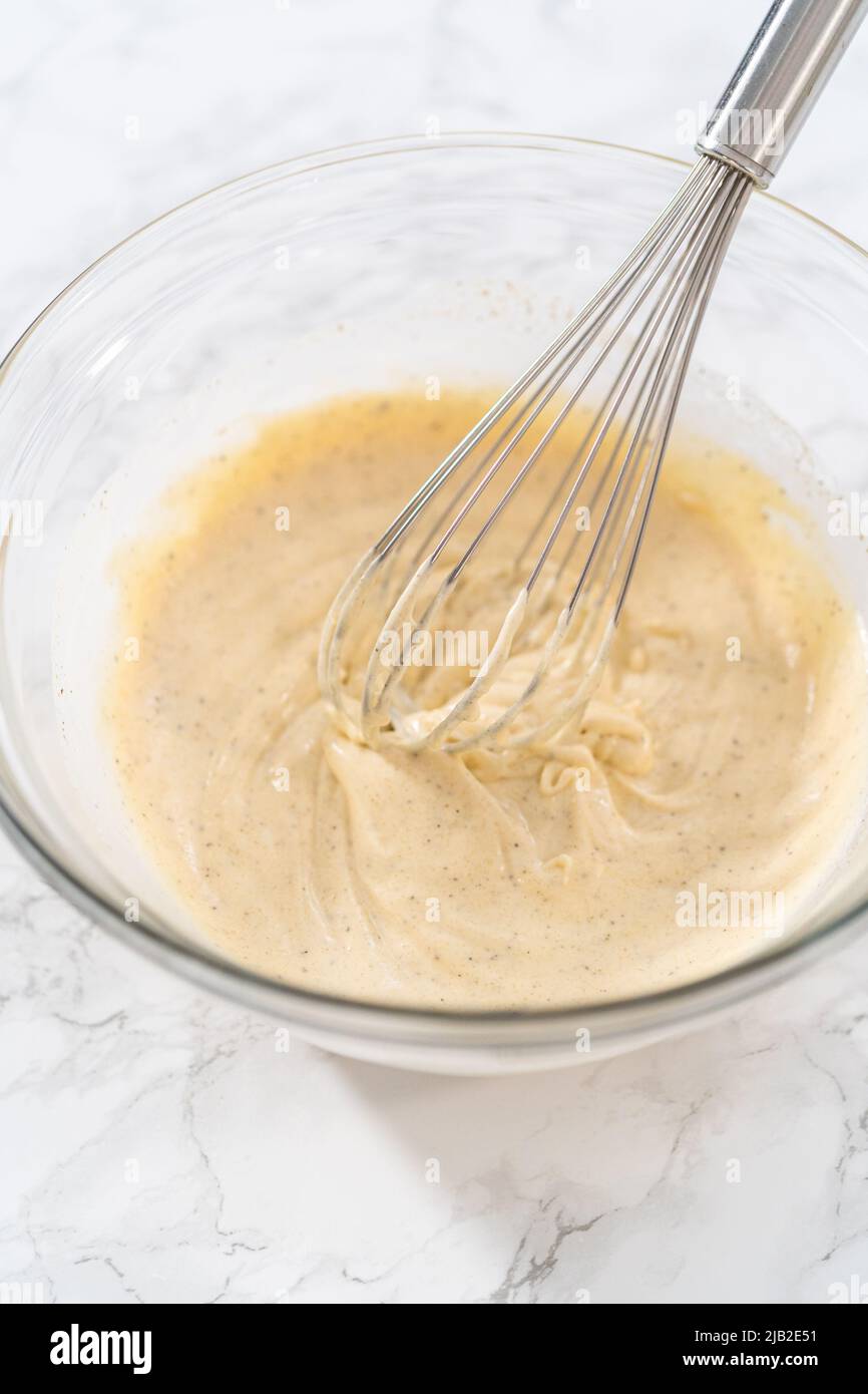 Mixing ingredients in a large glass mixing bowl to make dressing for ...