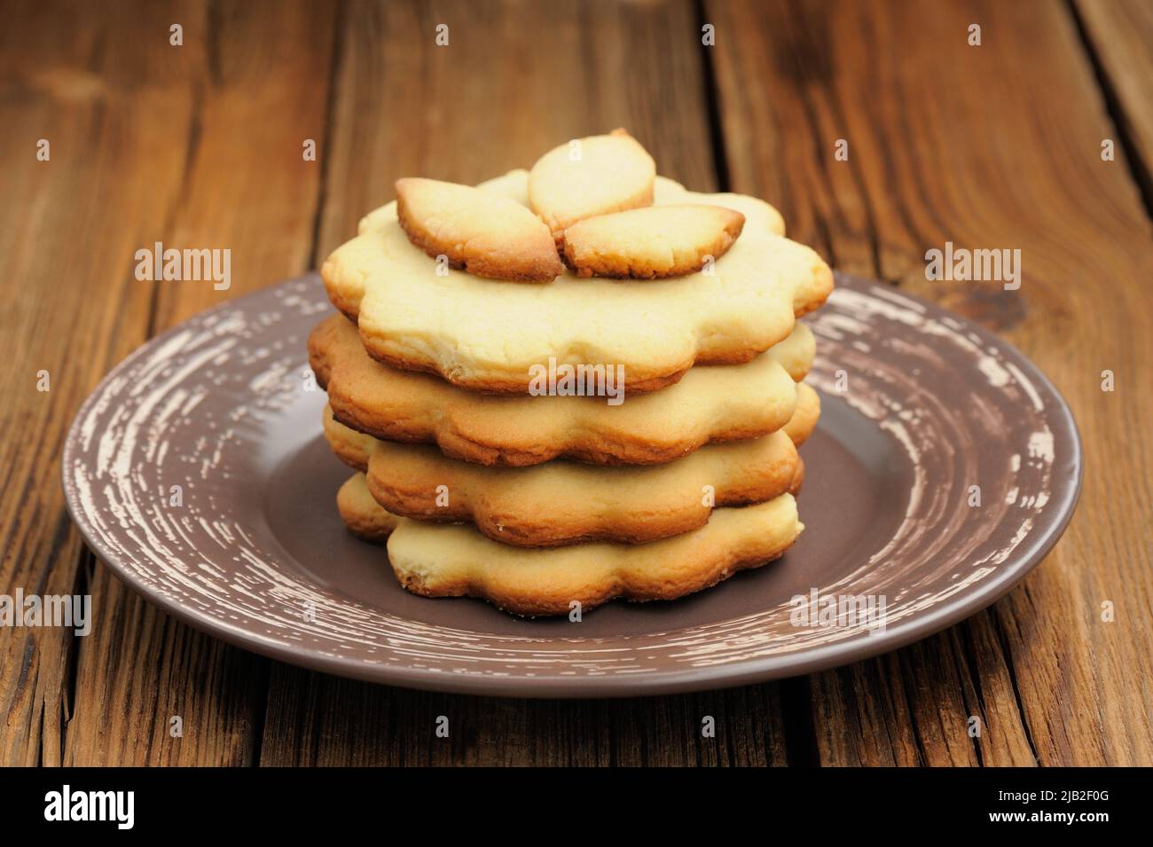 Round wavy sand cakes in pile decorated with small cakes on brown plate ...