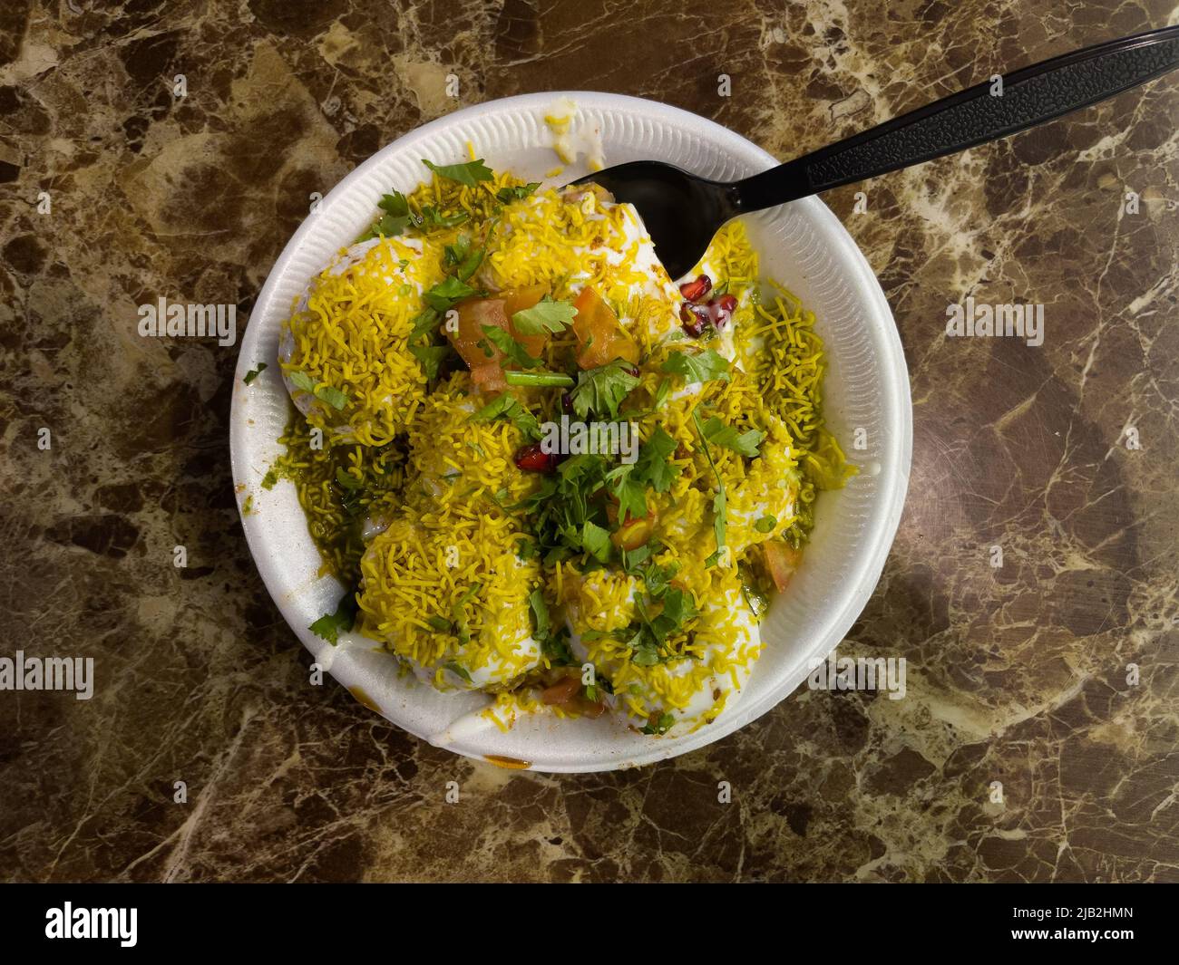 Top view of Dahi sev puri served in a disposable bowl and placed on a ...