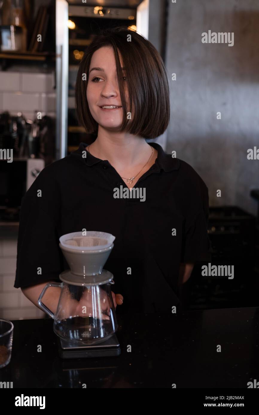 charming brunette woman barista making filter coffee in coffee shop ...