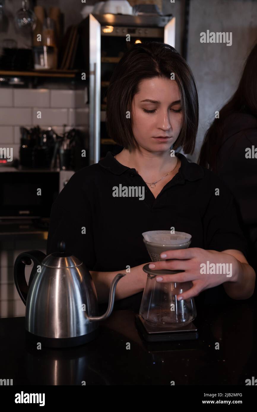 charming brunette woman barista making filter coffee in coffee shop ...