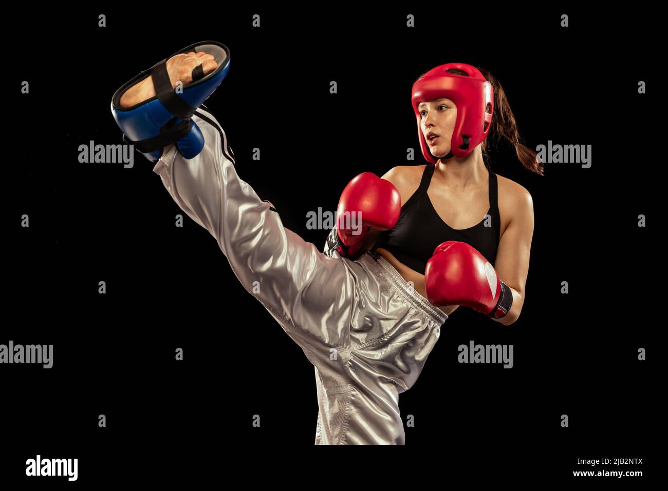 Sportive woman, professional boxer in boxing gloves and helmet training ...