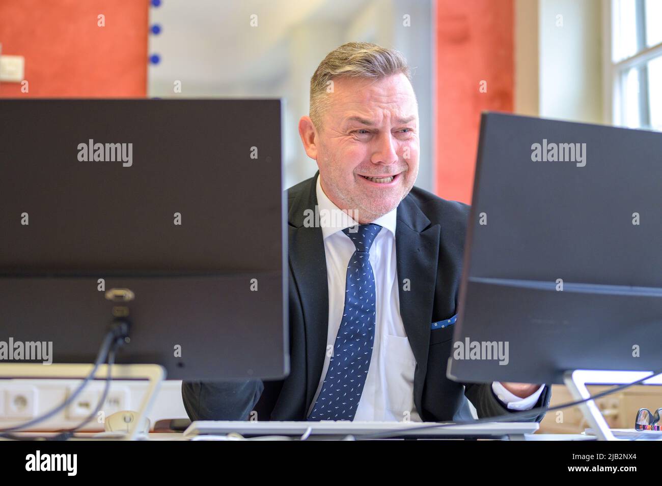 Distraught businessman grimacing at his computer screen viewed between ...