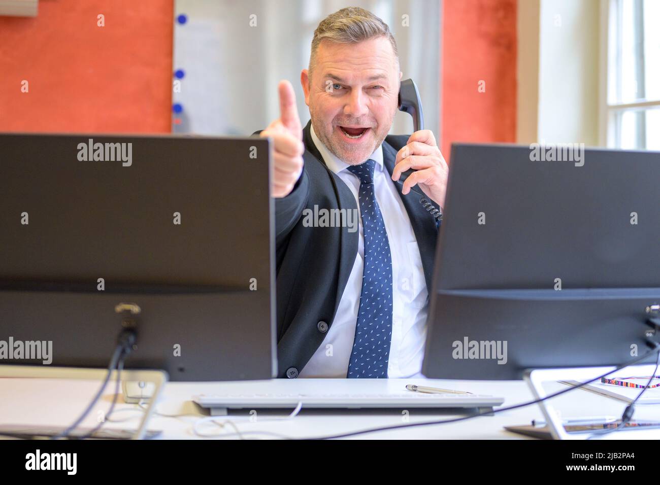 Enthusiastic successful businessman giving a thumbs up with a satisfued ...