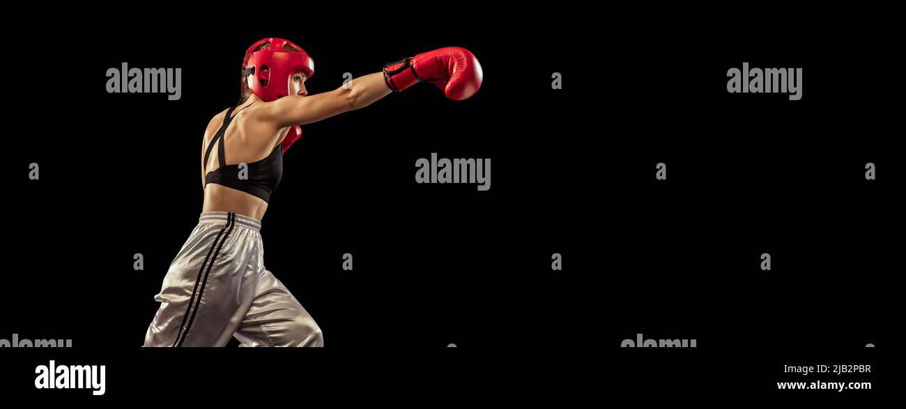 Young female boxer in boxing gloves and helmet training isolated on ...