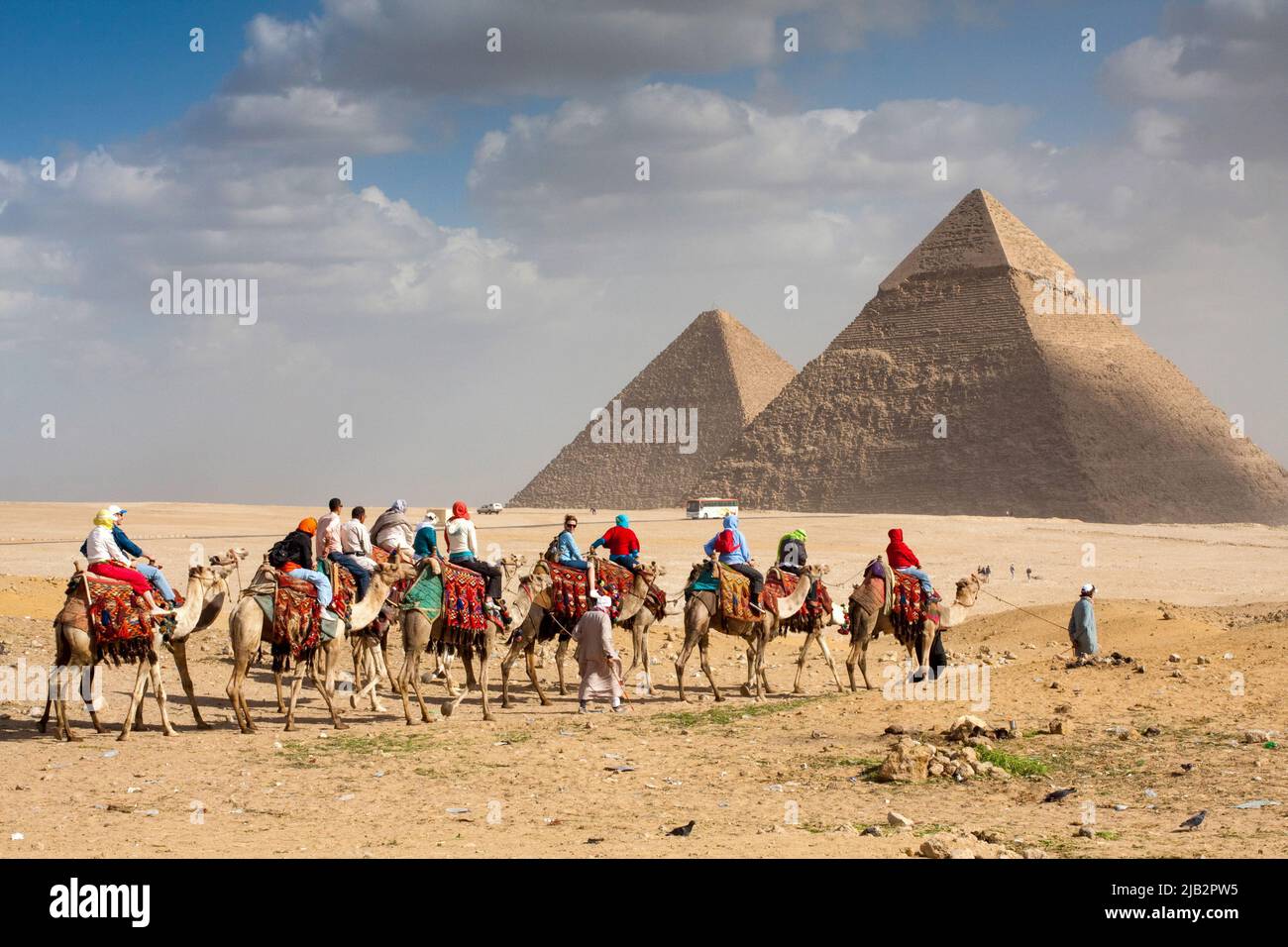 Egypt, Cairo. Tourists having a camel ride around the Giza pyramids ...