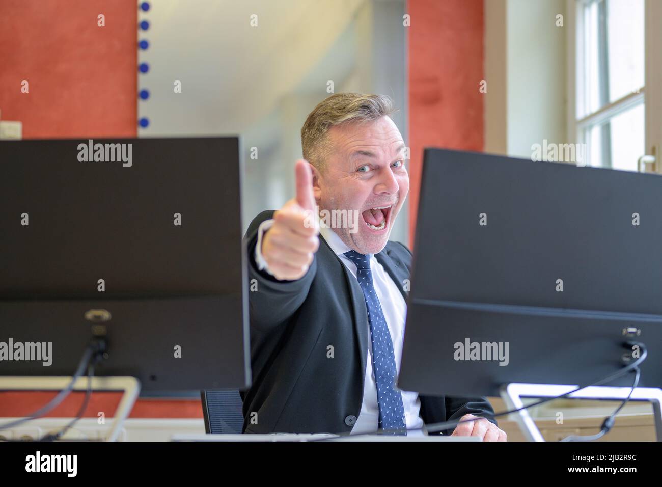 Excited businessman giving a thumbs up and cheering celebrating a ...