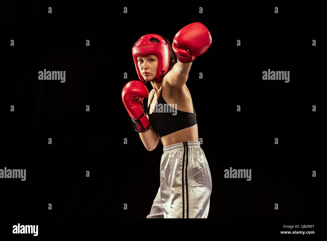 Professional female boxer in boxing gloves and helmet training isolated ...