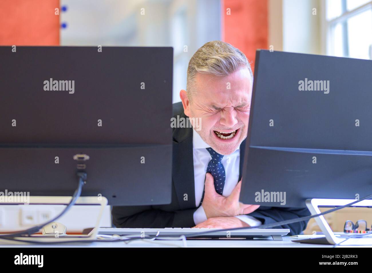 Businessman suffering a heart attack or infarct clutching his chest in ...