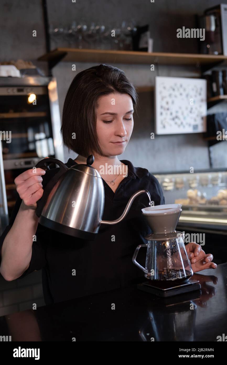 charming brunette woman barista making filter coffee in coffee shop ...