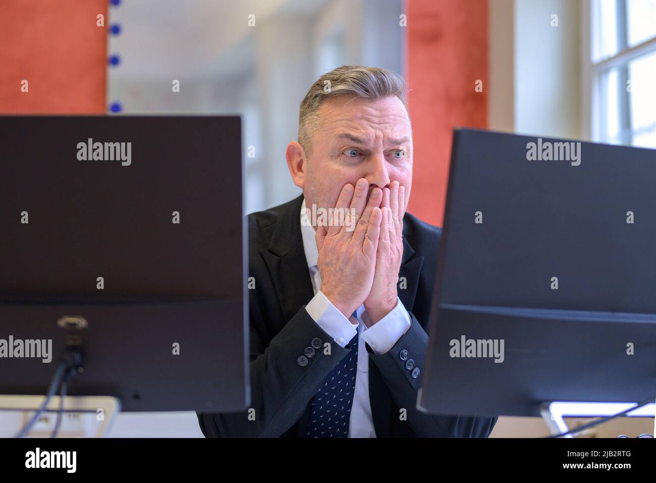 Aghast businessman looking at his computer screen with his hands to his ...