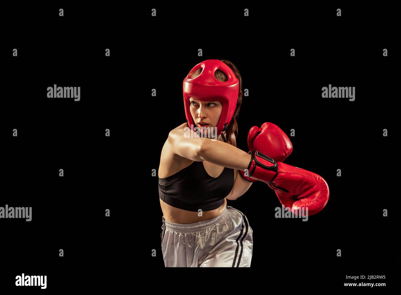 Professional female boxer in boxing gloves and helmet training isolated ...