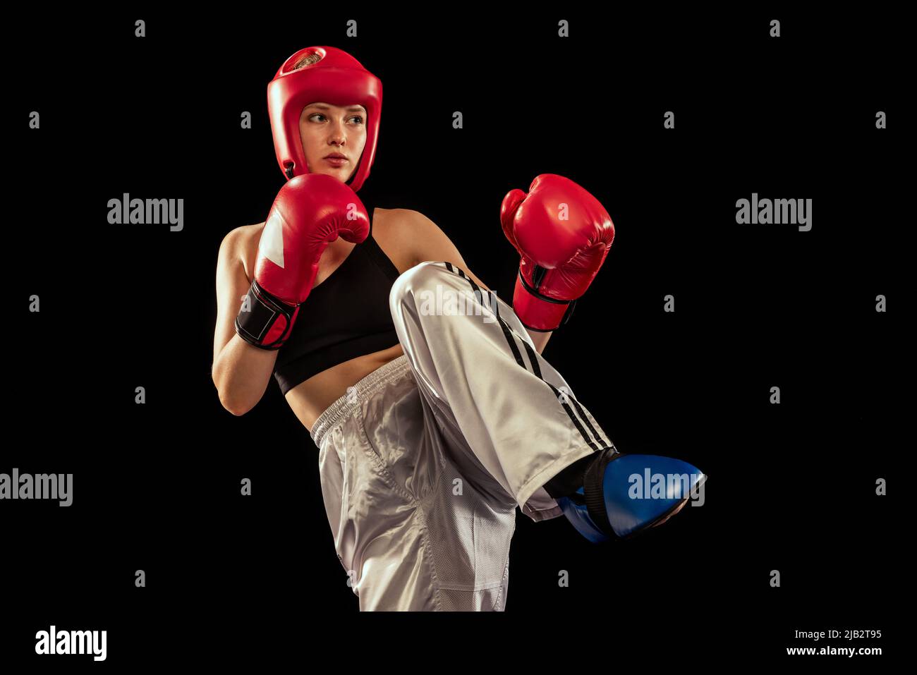 Professional female boxer in boxing gloves and helmet training isolated ...
