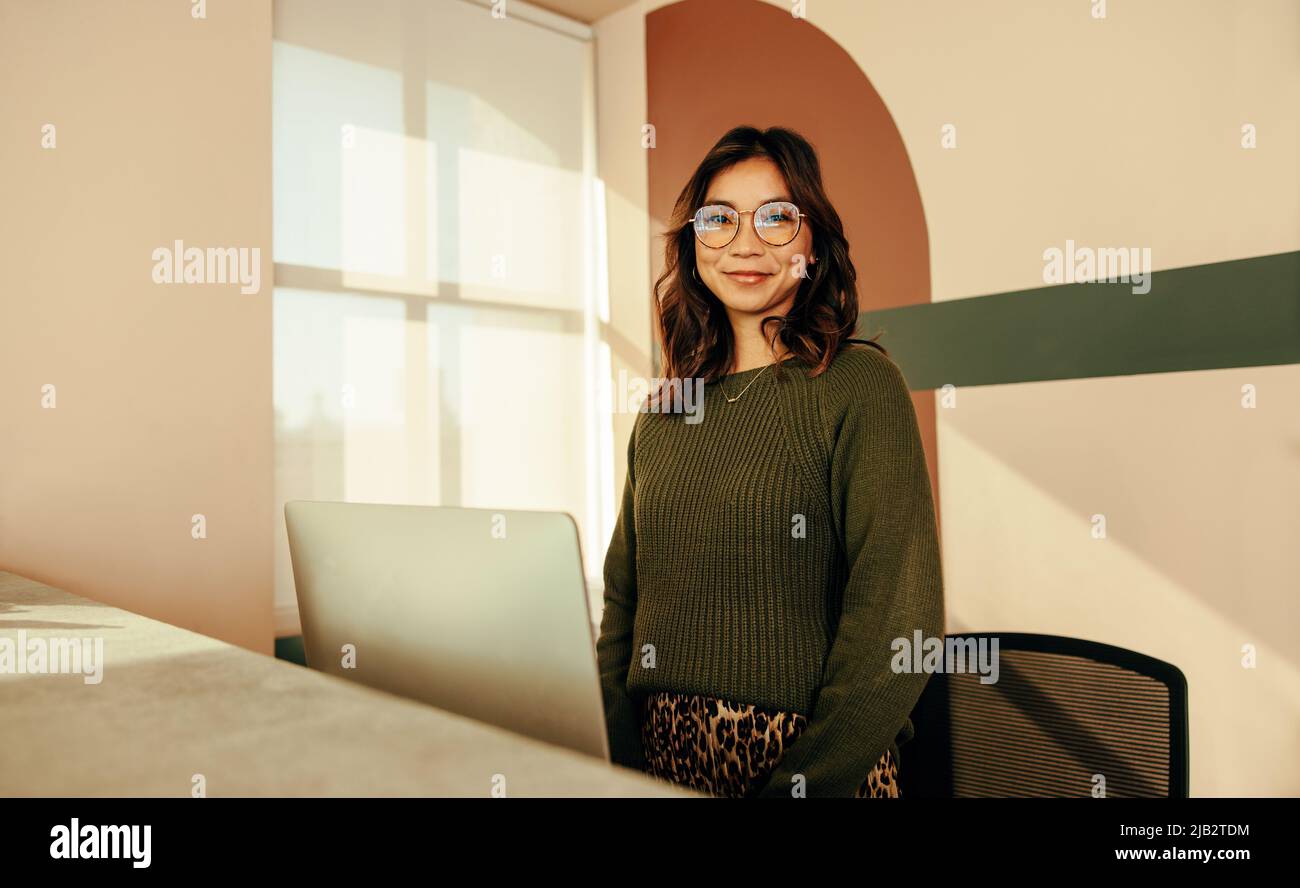 Cheerful receptionist standing at the front desk of a co-working space ...
