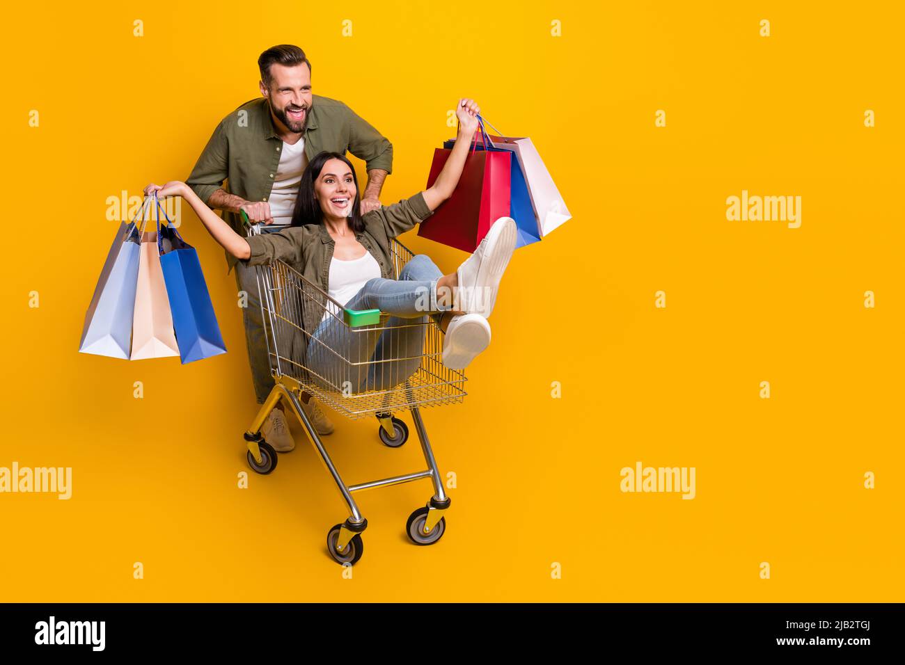 Full size photo of young cheerful couple have fun drive cart store ...
