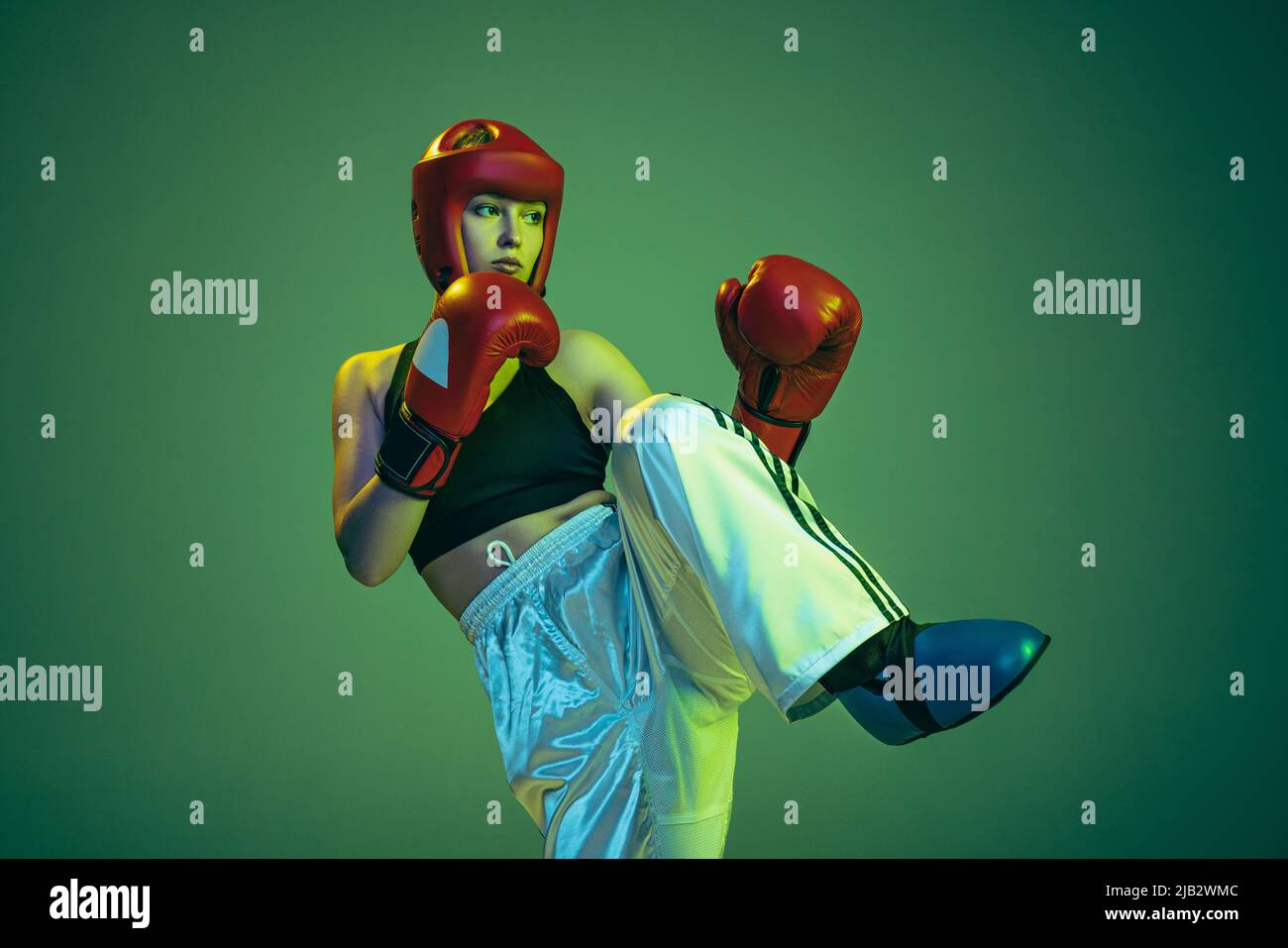 Knee kick. Caucasian female boxer in boxing gloves and helmet ...