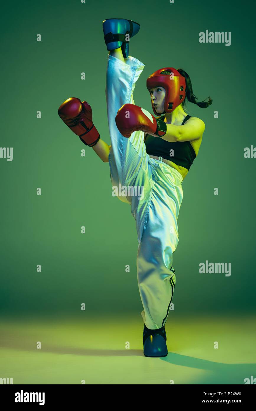 Stretching. Young female boxer in boxing gloves and helmet practicing ...