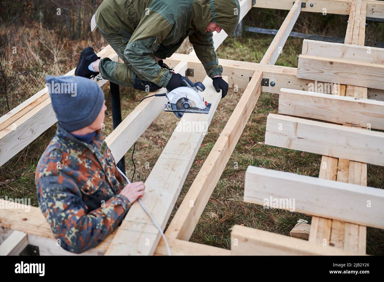 Carpenter using circular saw for cutting wood beam. Man worker building ...