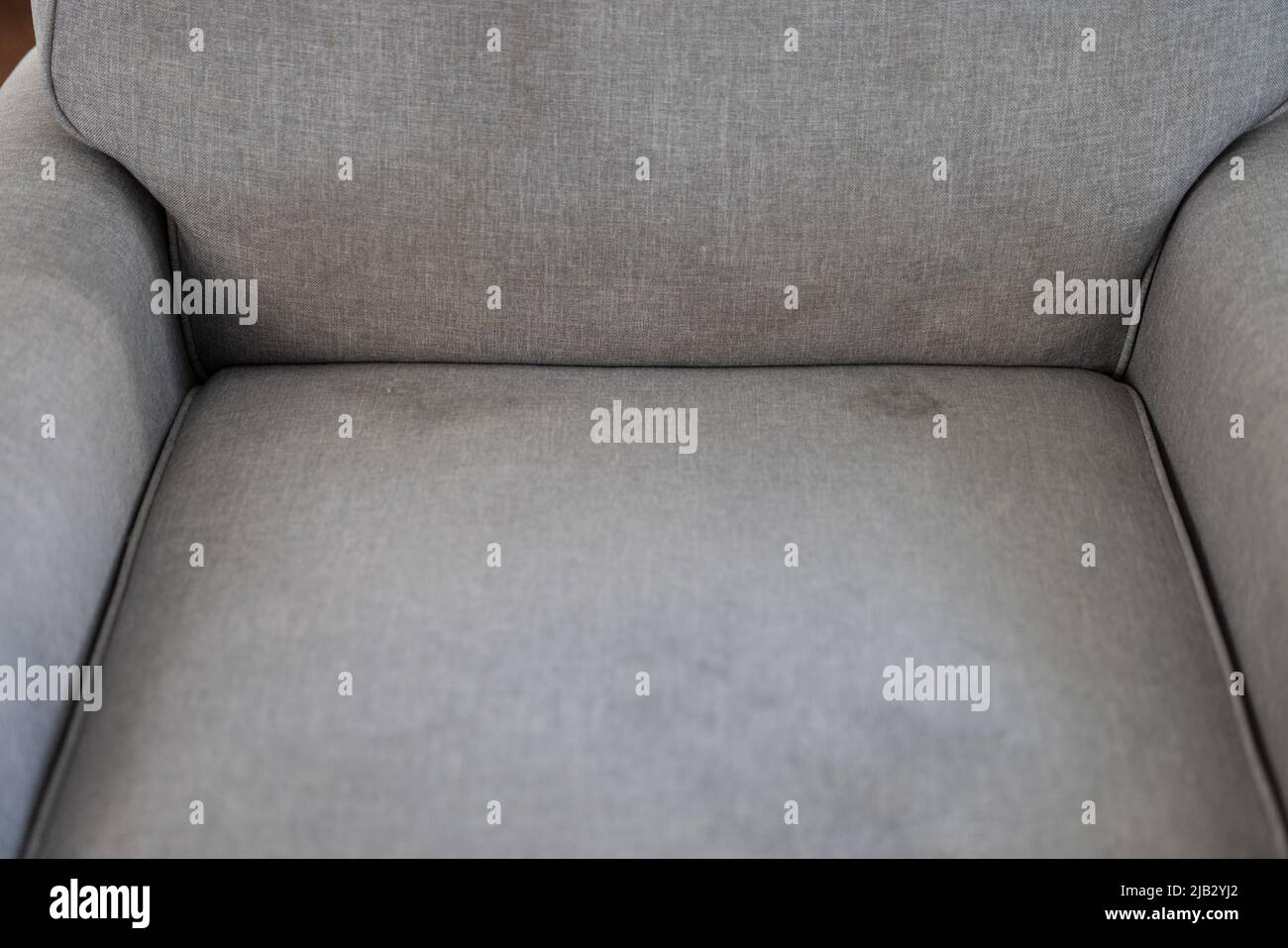 Close up view of a stained upholstered living room chair that needs to ...